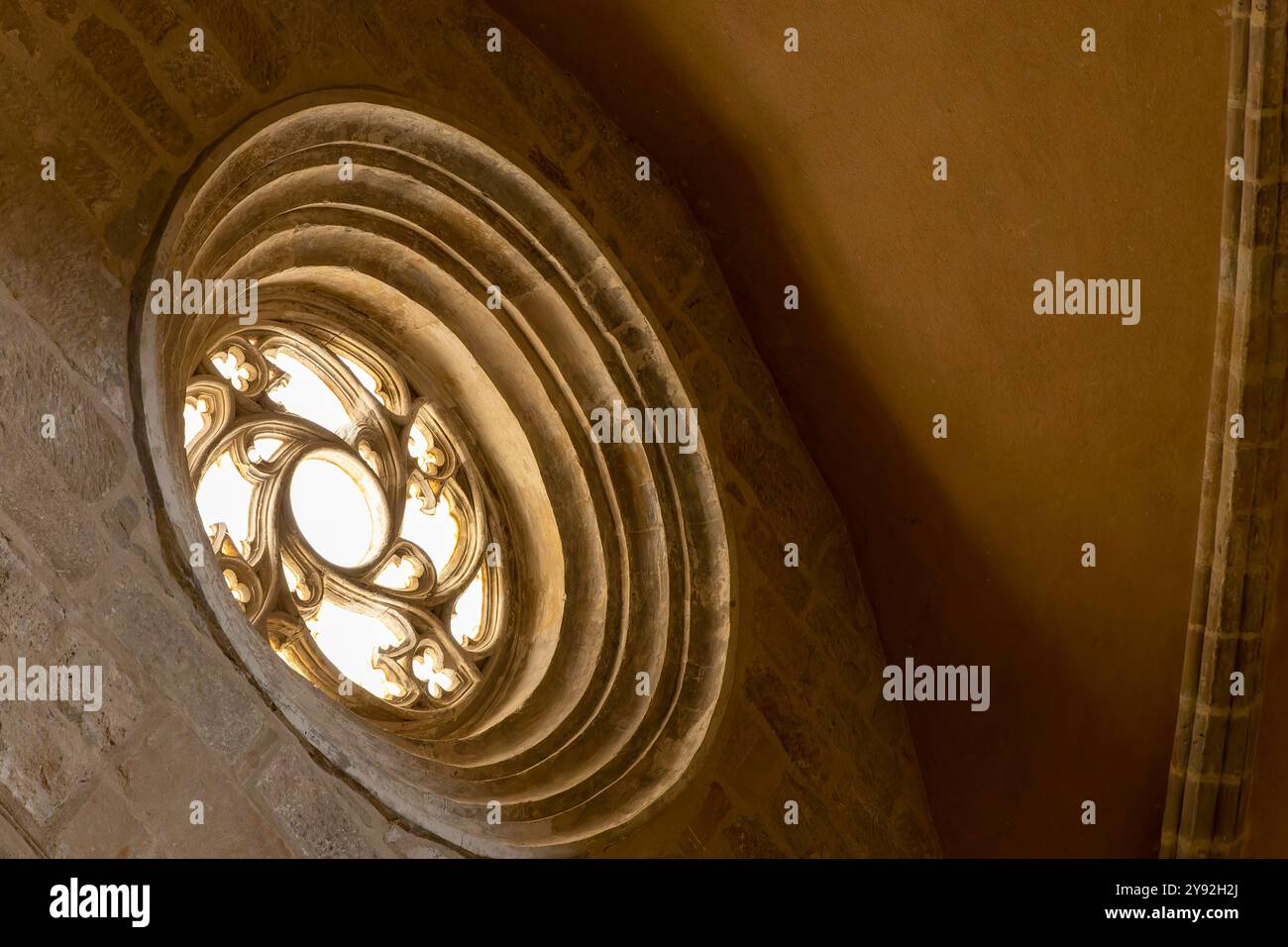 A window with a circular design is lit up by the sun. Gothic rose ...