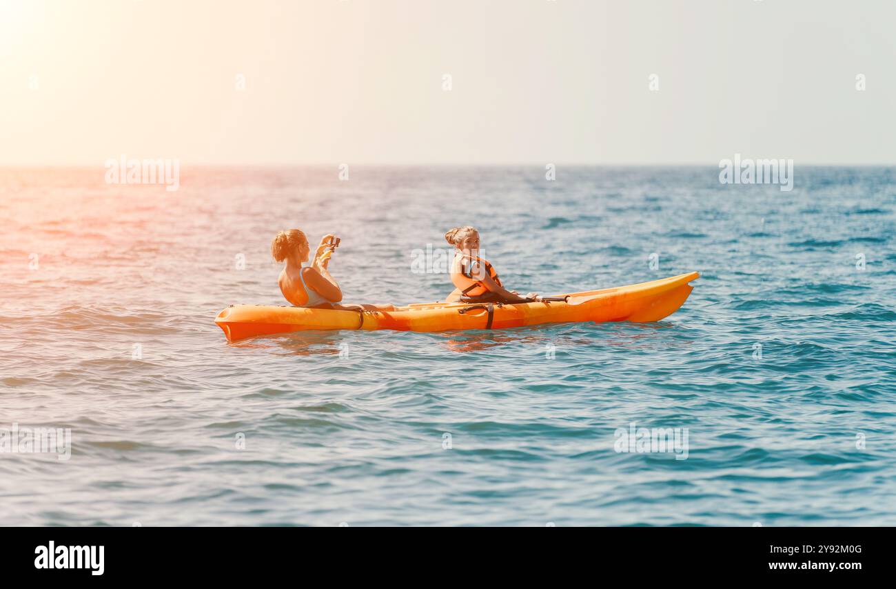 Two young women in a kayak on a calm ocean, one taking a photo while ...