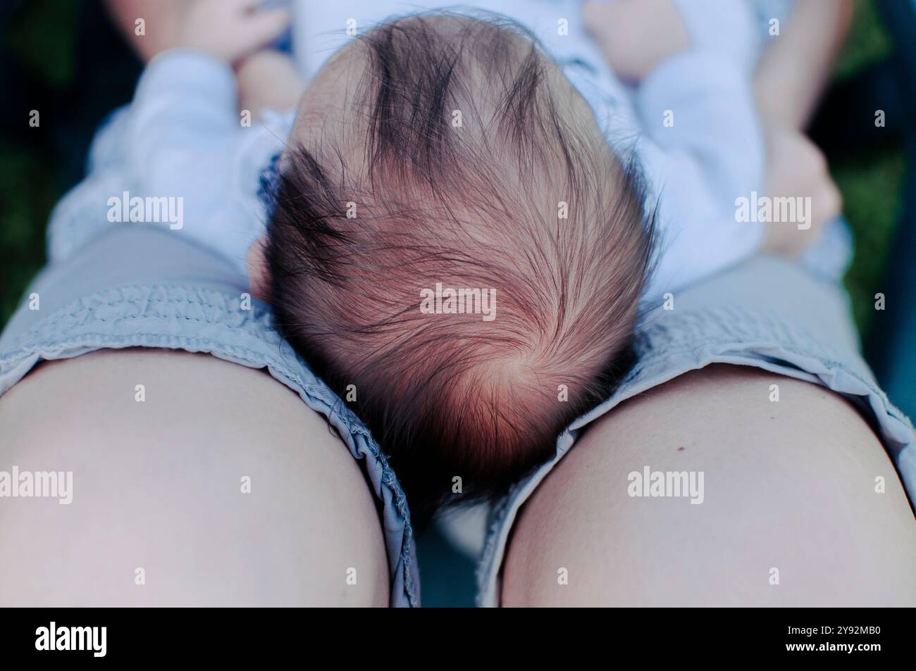Newborn baby's head resting on mother's legs Stock Photo - Alamy