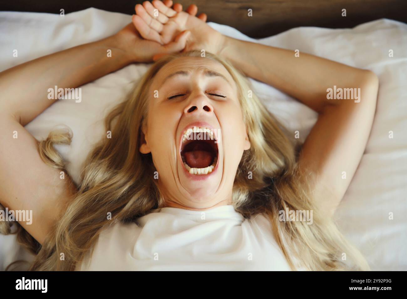 Sleepy lazy woman yawns waking up after sleeping lying on the bed wakes ...