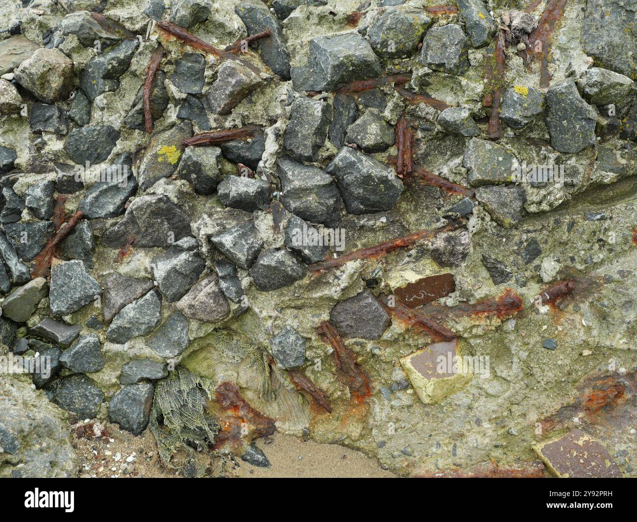 Concrete debris with rusted iron on the beach, relics of an old harbor ...