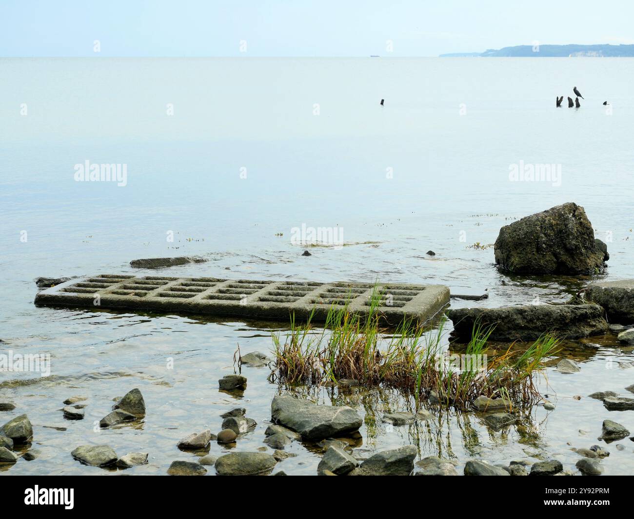 Old road slabs and construction debris rot on the beach. Harbor relics ...