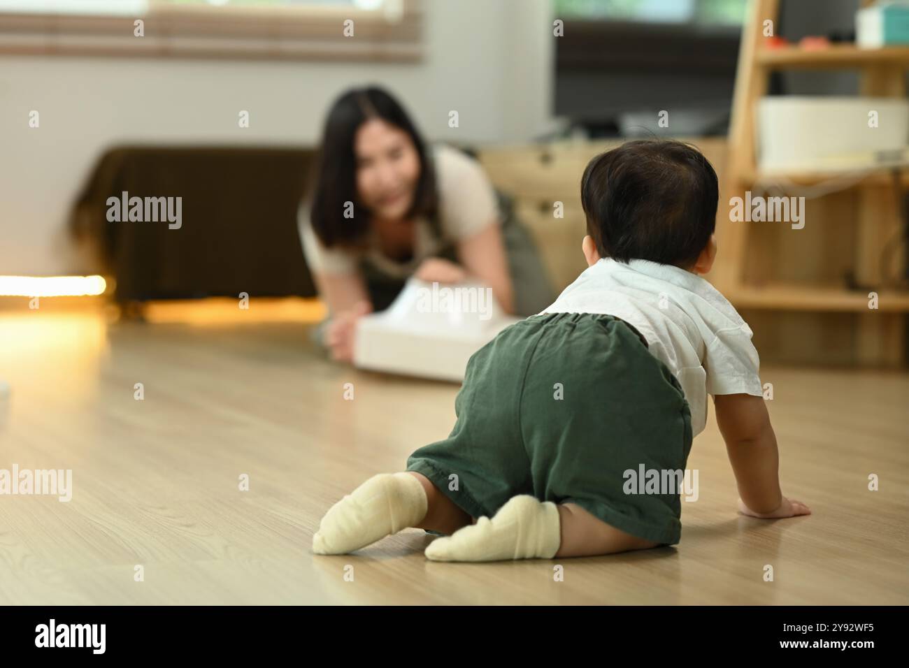 Cute baby boy crawling on the floor towards mother. Parenting, child ...
