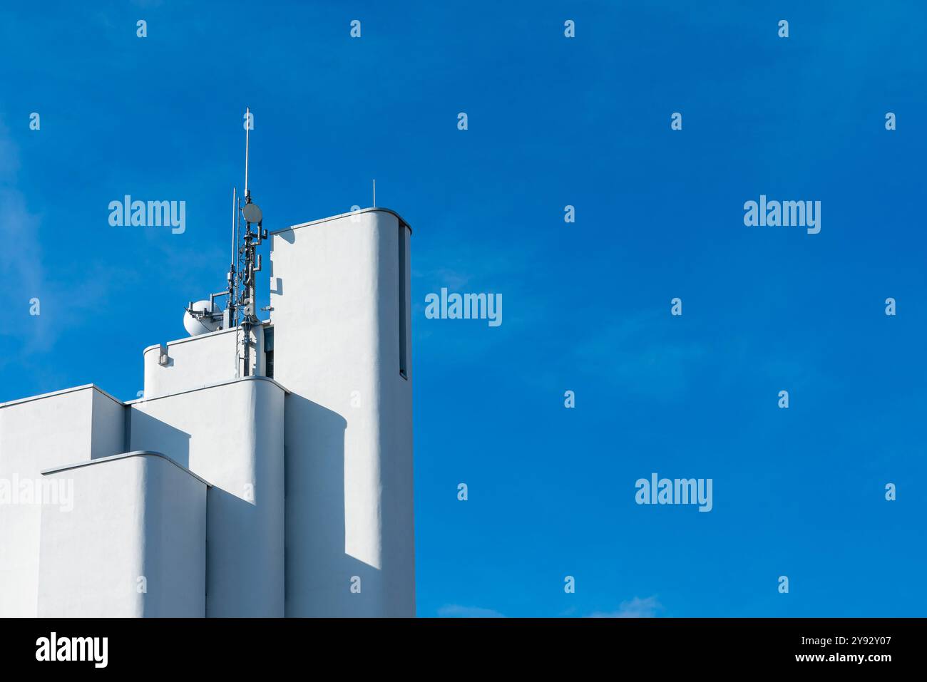 A sleek communication tower stands prominently against a clear blue sky ...
