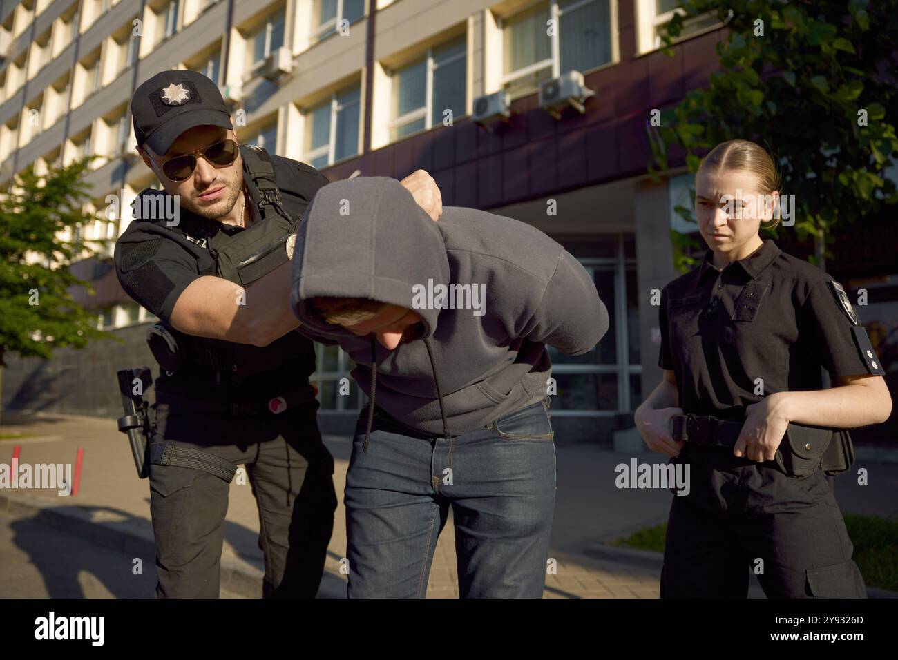 Two police officers providing arrest of criminal in act on city street ...