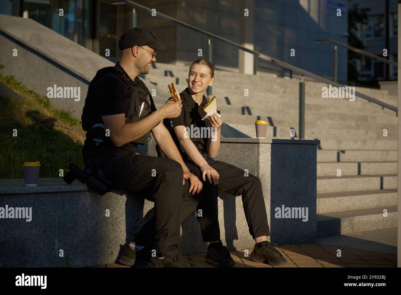 Smiling male and female patrol police officers enjoying lunch break ...