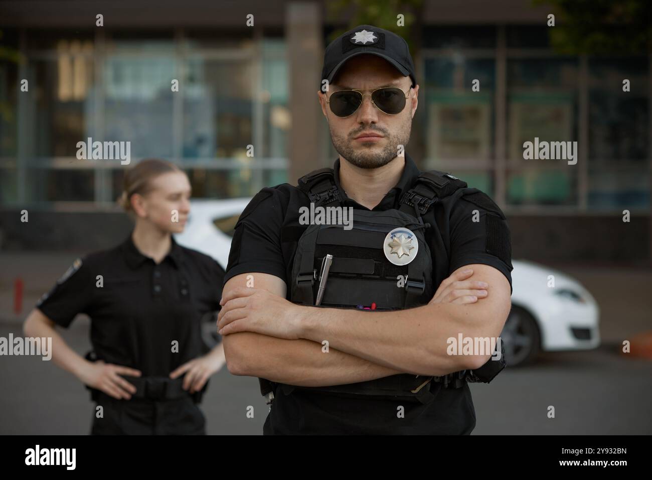 Serious brave man patrol police officer with policewoman on background ...