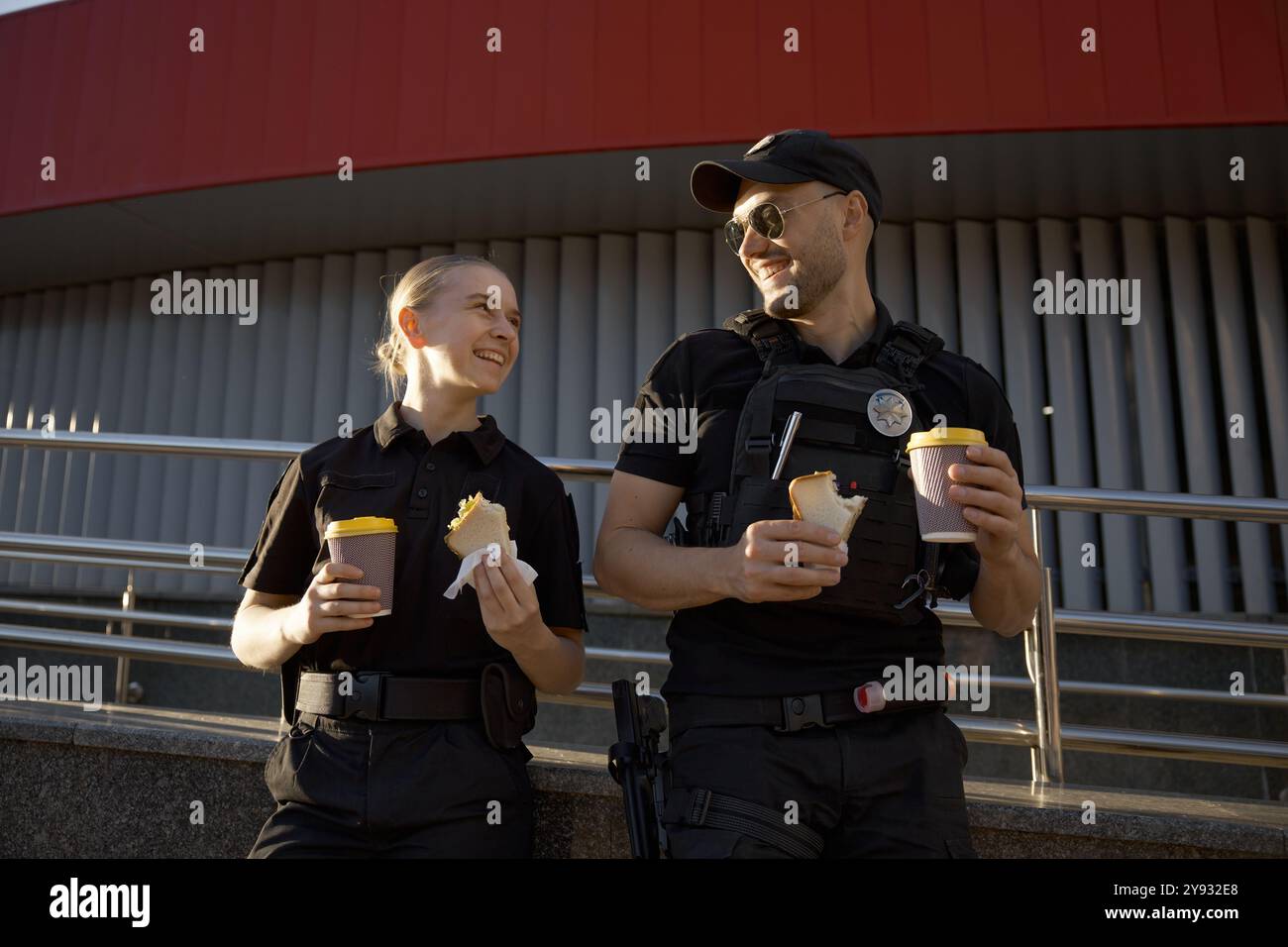 Male and female patrol police officers enjoying lunch break outdoor ...