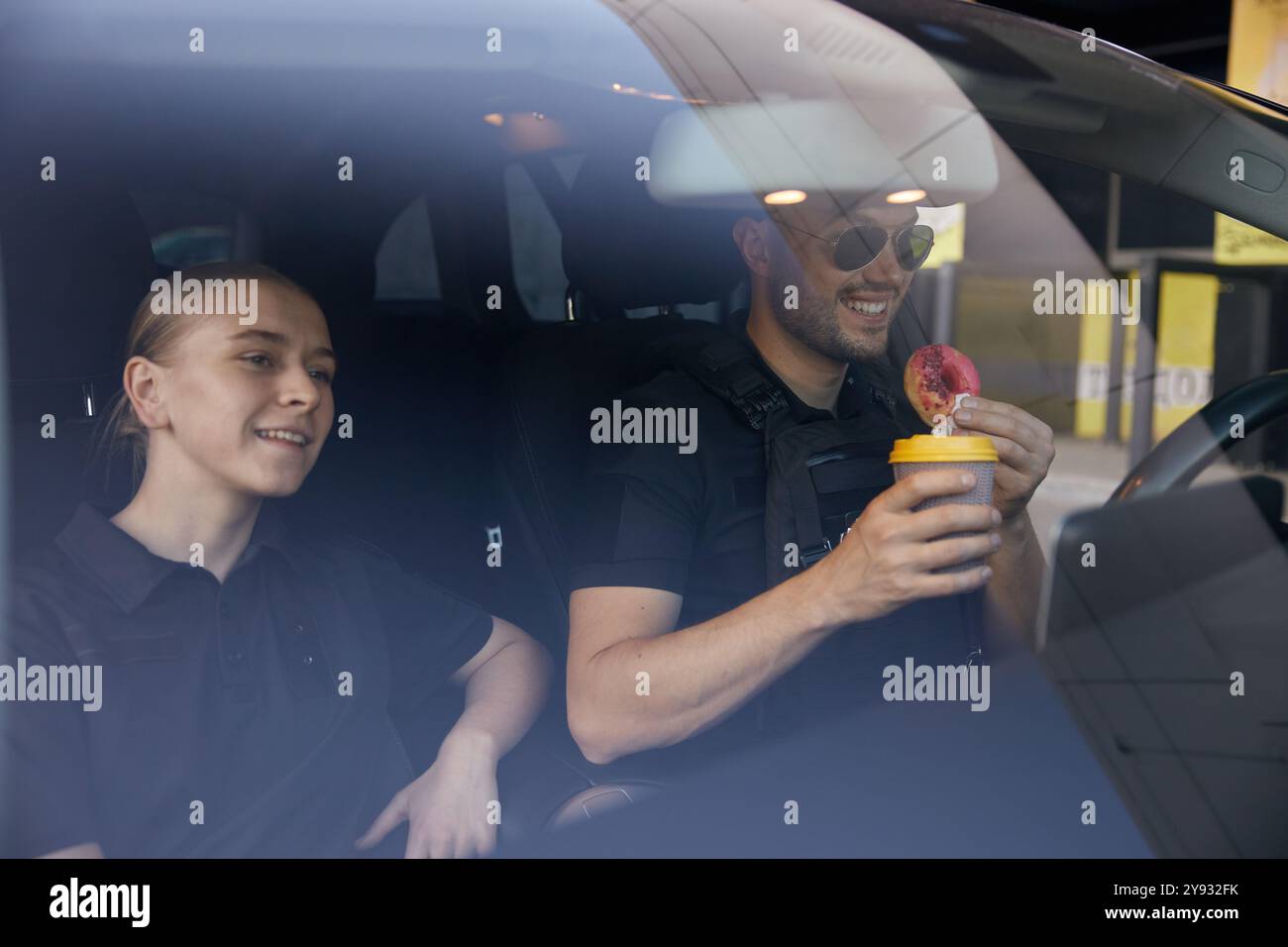 Patrol police officers diverse team sitting in car having coffee break ...