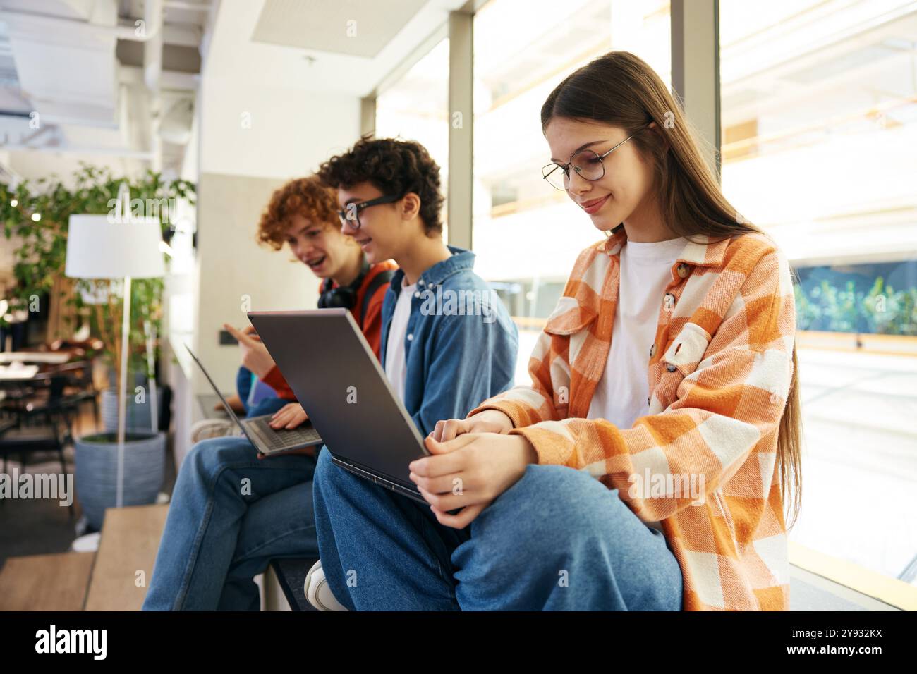 Teenagers working in office using their laptops Stock Photo - Alamy