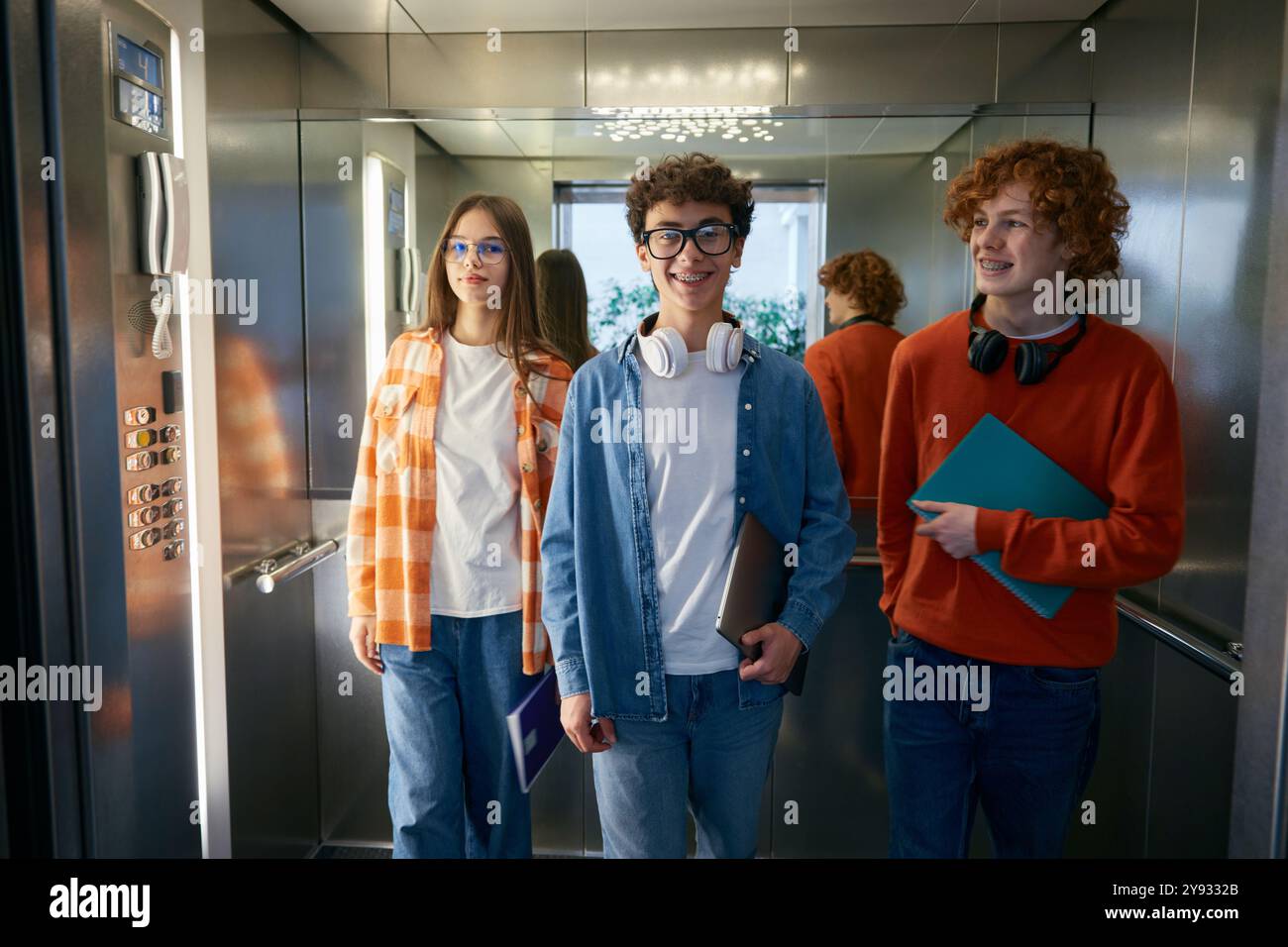 Three teenagers standing inside the elevator holding folder with papers ...