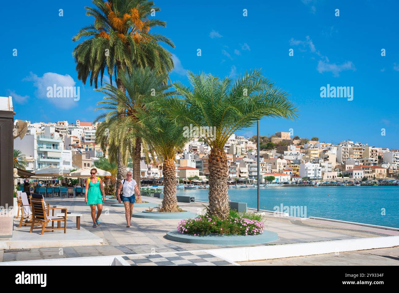 Greece holiday vacation, view of two young women walking along the palm ...