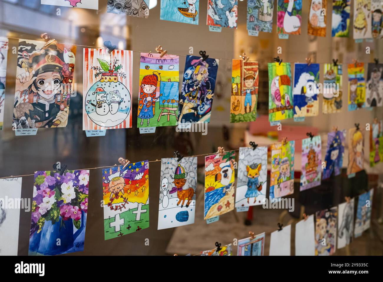Colorful children drawings hang on a stand. Many children drawings hang ...