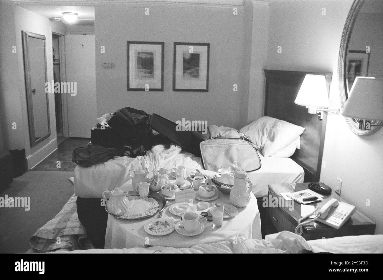 hotel room in disarray with suitcase on the bed and remains of ...