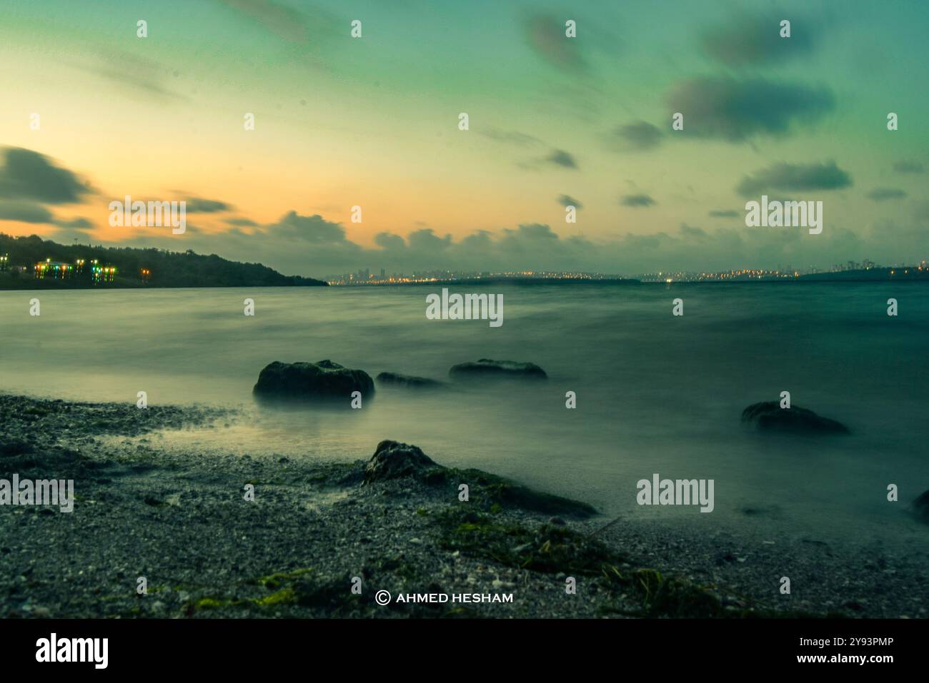 The image captures a serene evening scene at a bay. The long exposure ...
