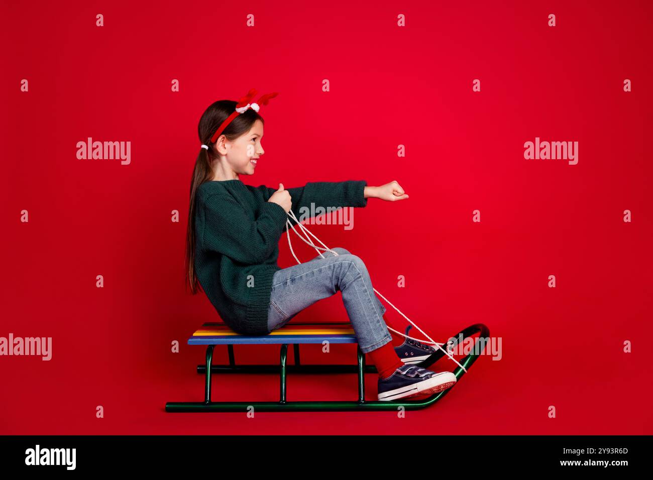 Full body photo of cute little girl superhero ride sledge dressed green ...