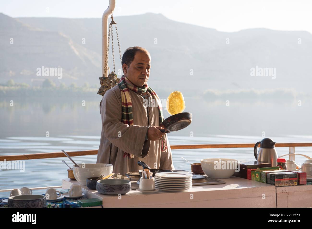 Cook preparing breakfast pancakes on the upper deck of the dahabeah ...