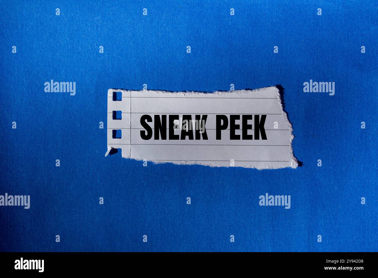 Sneak peek message written on ripped torn paper piece with blue background. Conceptual sneak ...