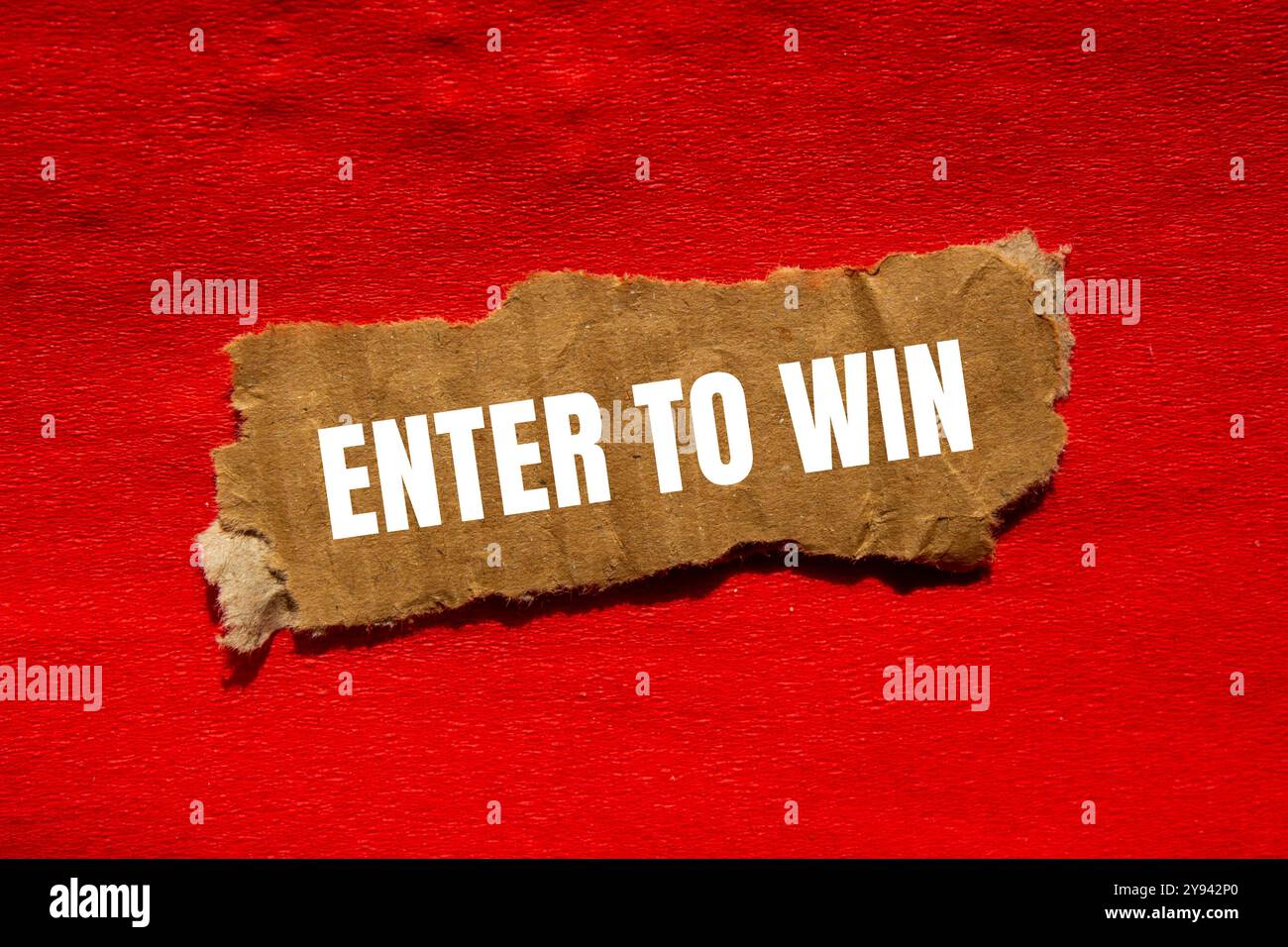 Enter to win message written on ripped torn cardbaord paper piece with ...