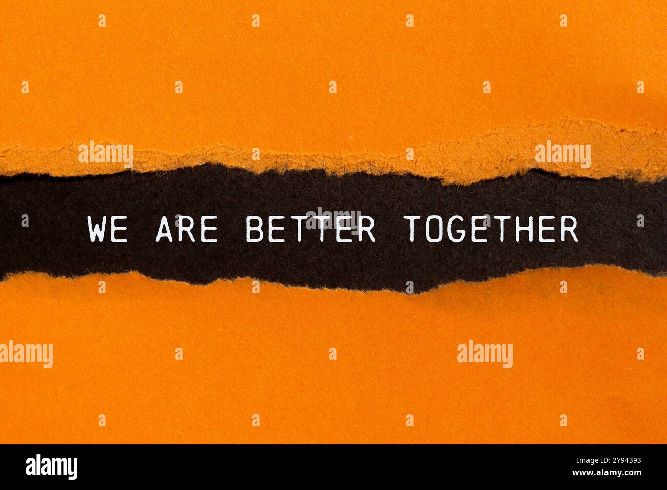 We are better together message written on ripped torn orange paper on black background ...