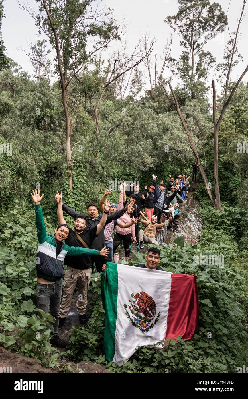 A spirited group of Mexican hikers waves and poses with a large Mexican ...