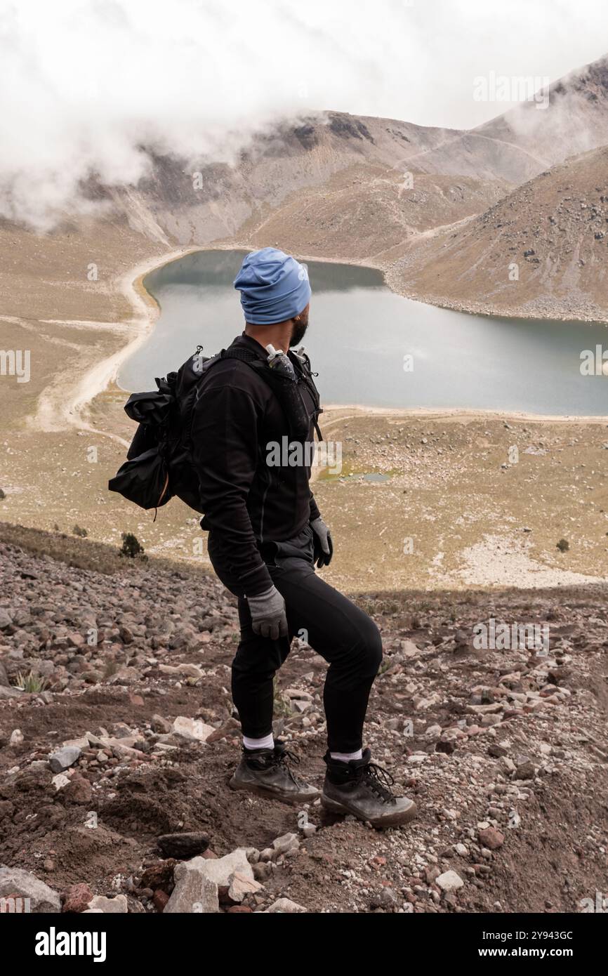Side view of unrecognizable man hiking along a rugged mountain trail ...