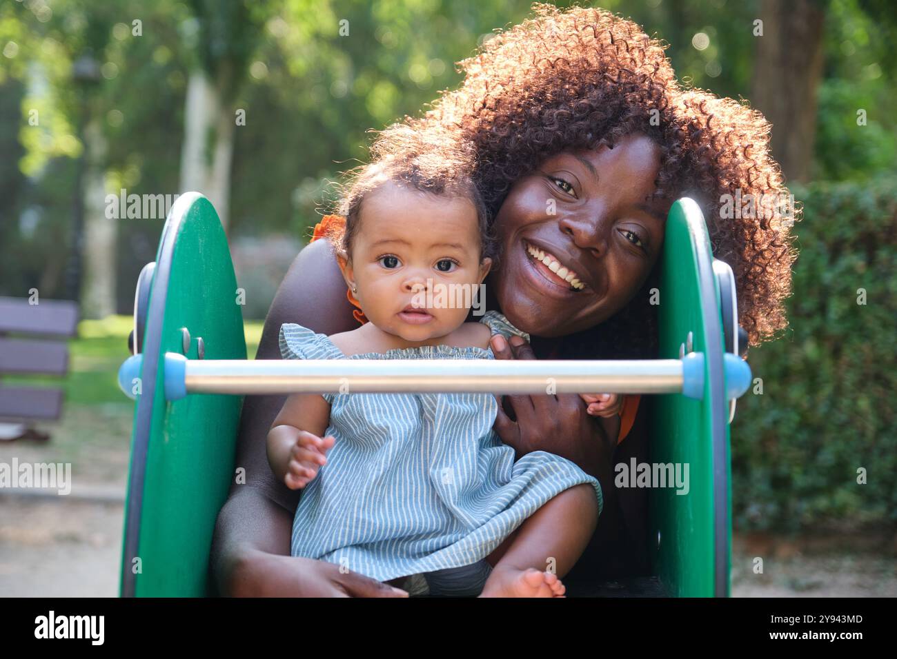An African mother smiling joyfully while holding her baby girl in a ...