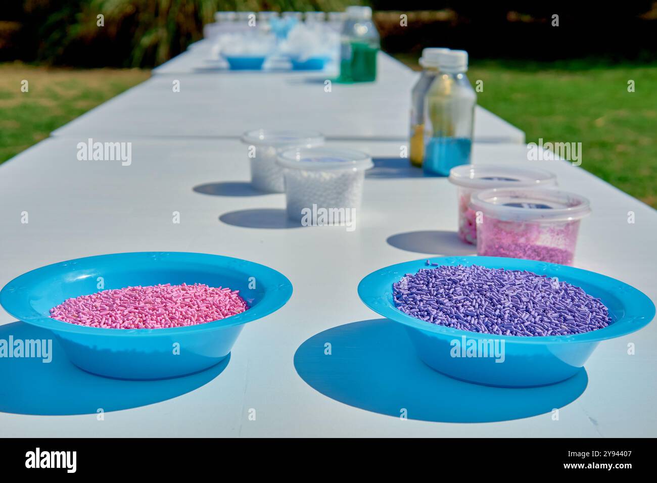 long white table with plates full of colourful sprinkles, along with ...