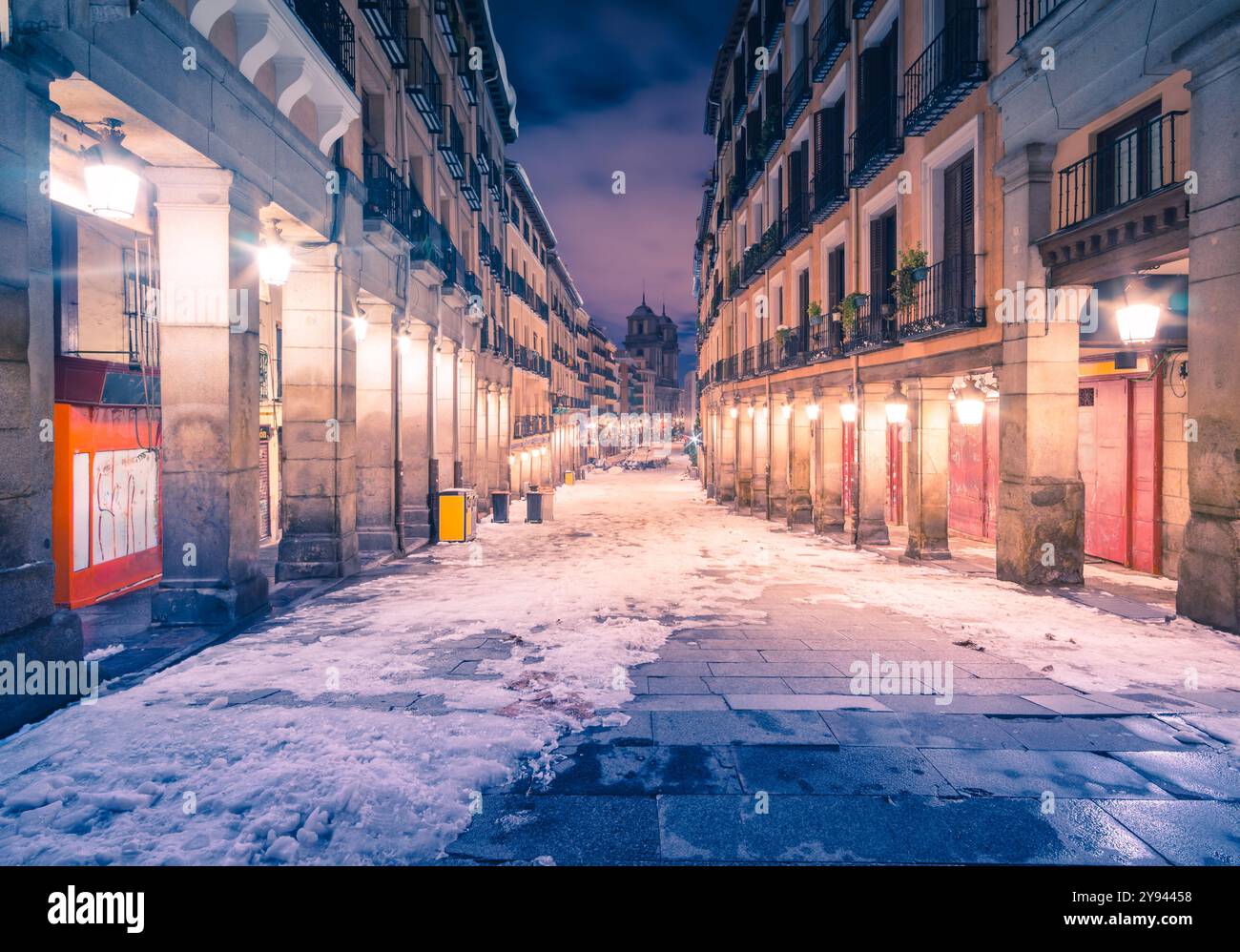 Snow covers a historic street in Madrid, Spain, highlighted by the warm ...