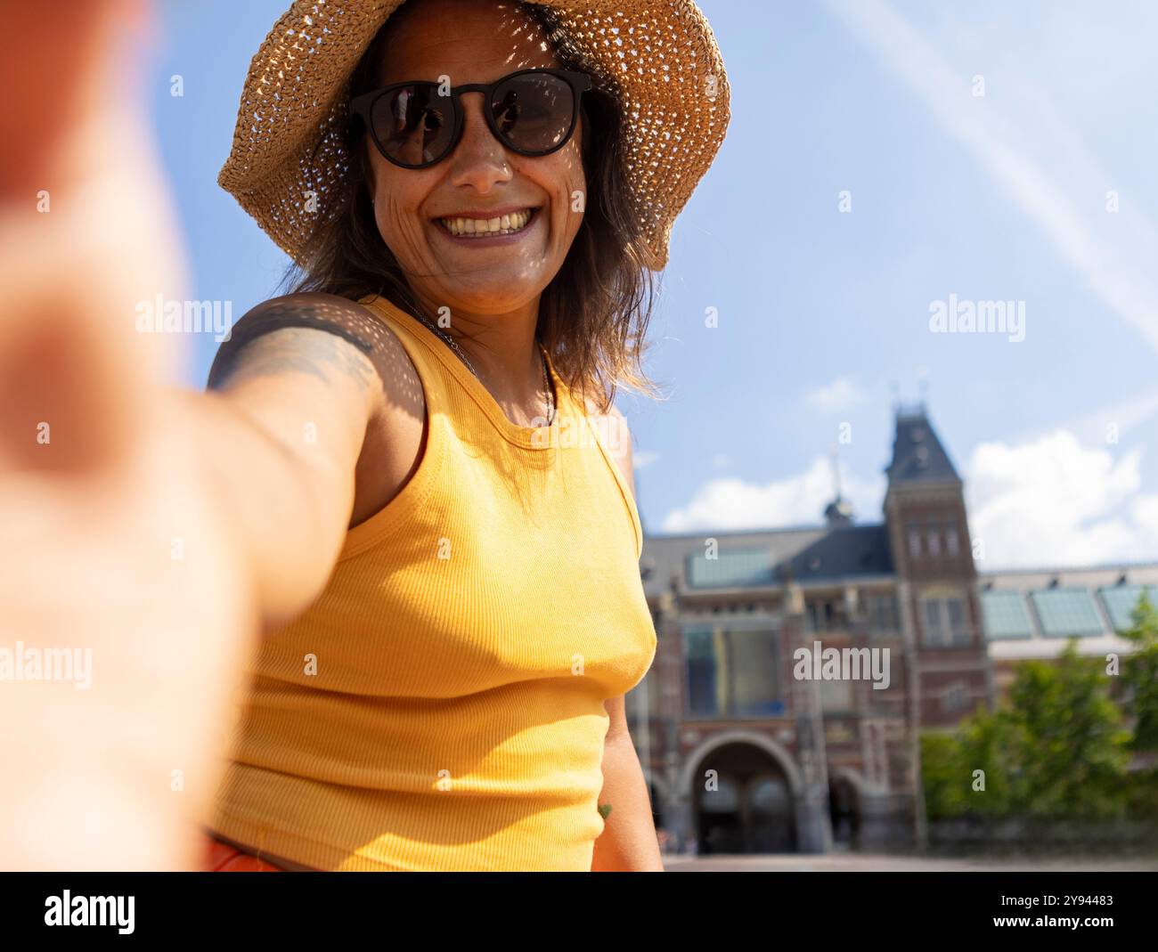 A cheerful woman, dressed in a summer outfit and wearing a straw hat ...