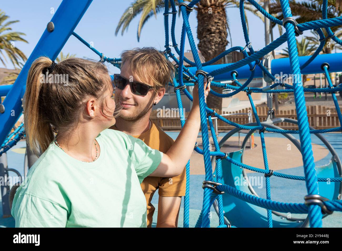 A young man and woman share a tender moment at a beachside playground ...