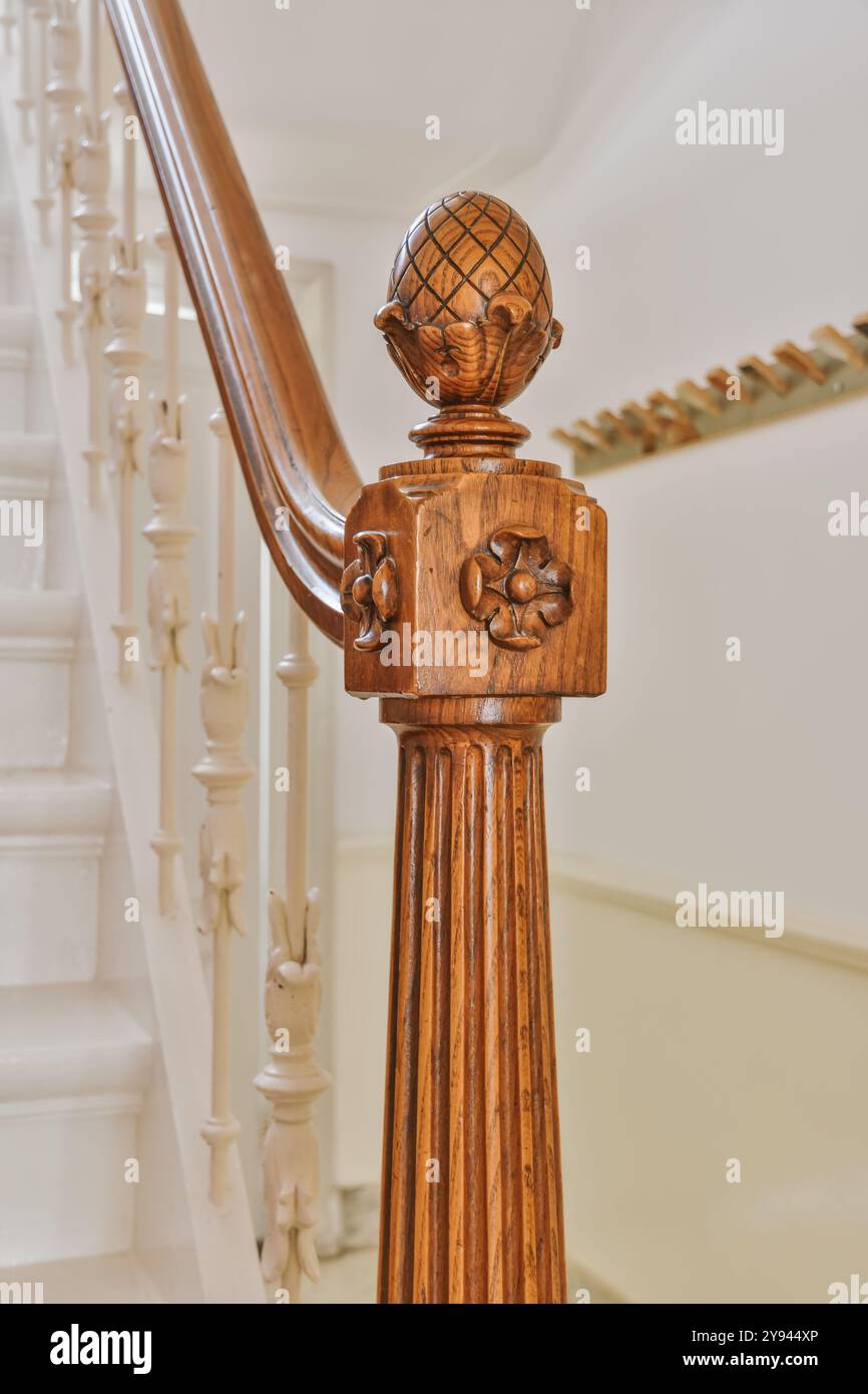 Elegant wooden newel post with intricate carving at the base of a ...