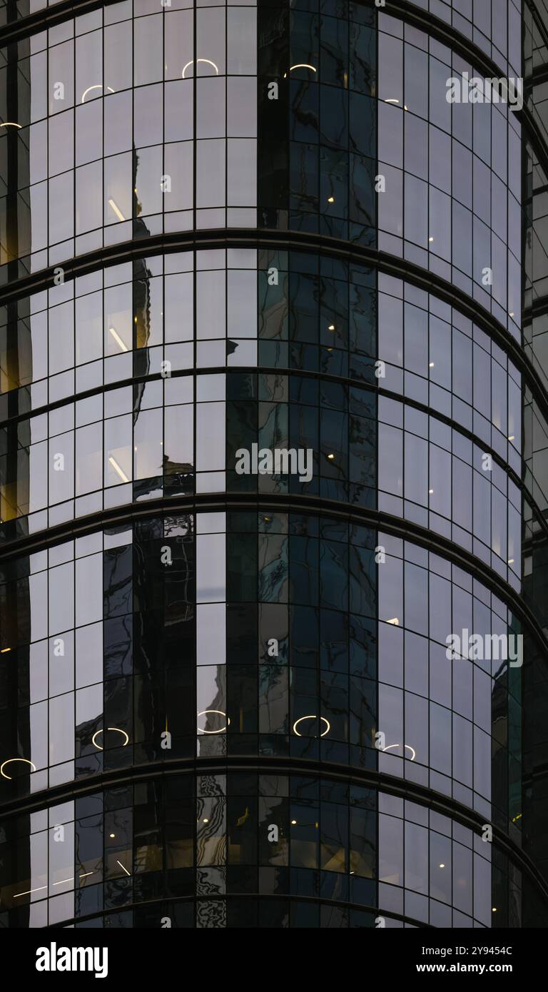 The image captures the sleek vertical facade of a modern glass office ...