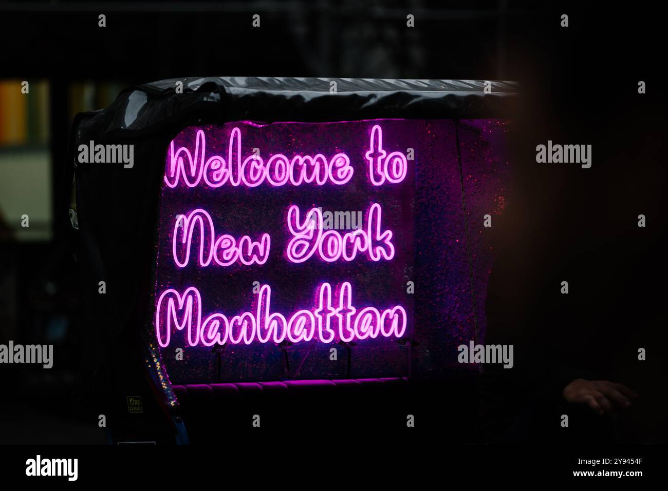 A bright pink neon sign saying "Welcome to New York Manhattan ...