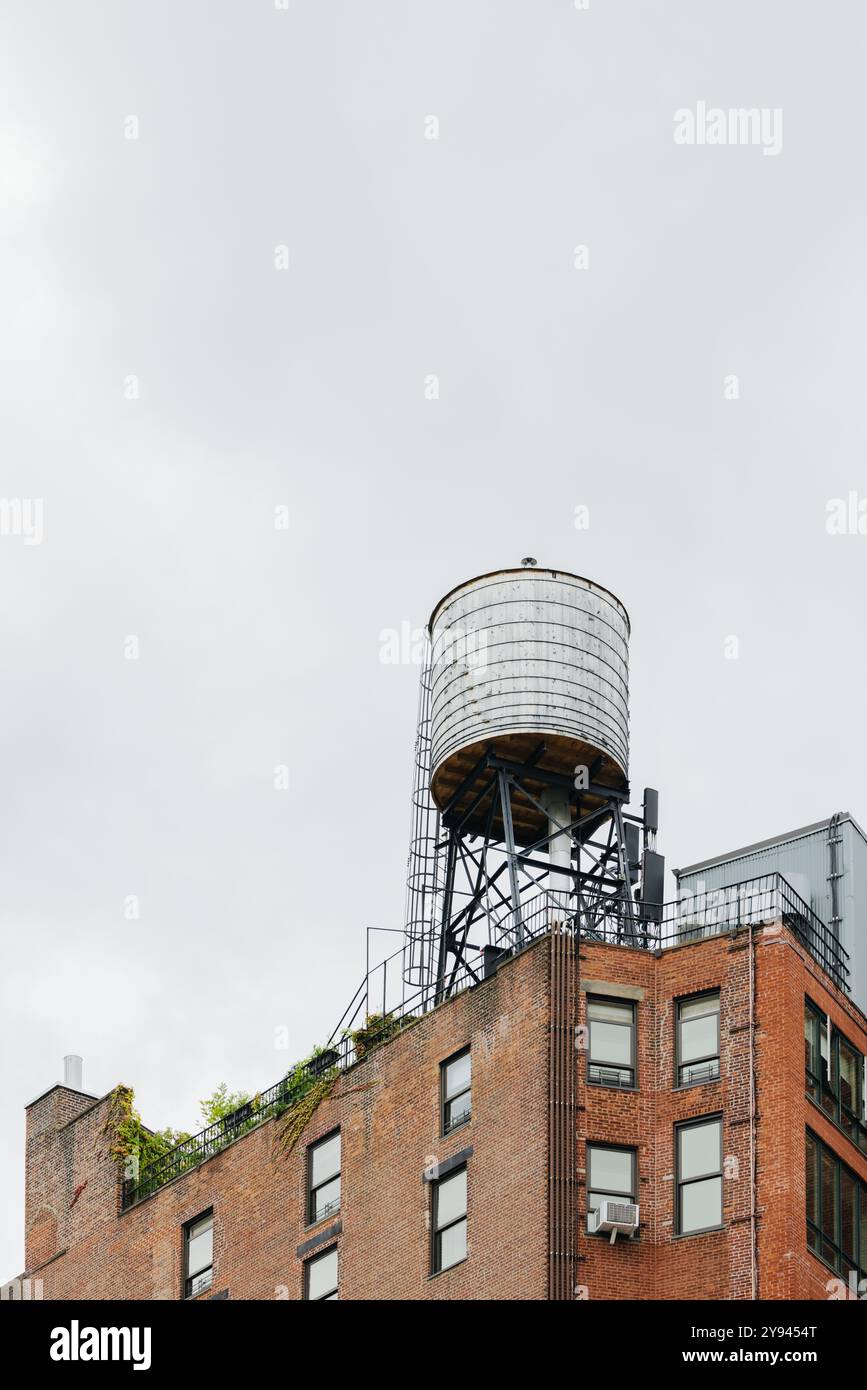 An aged water tank sits atop a brick building roof in New York. The ...