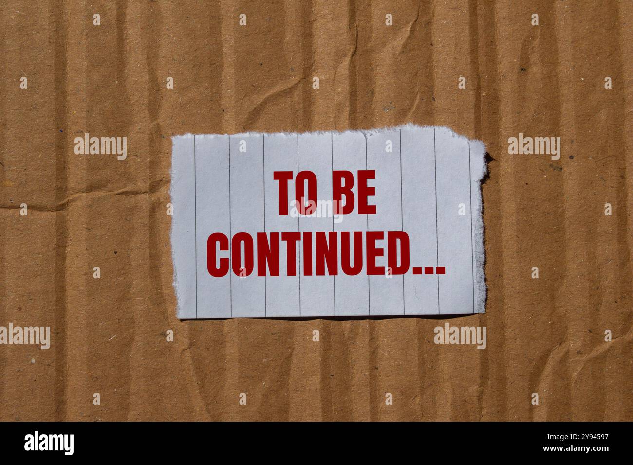 To be continued message written on ripped torn paper with cardboard ...
