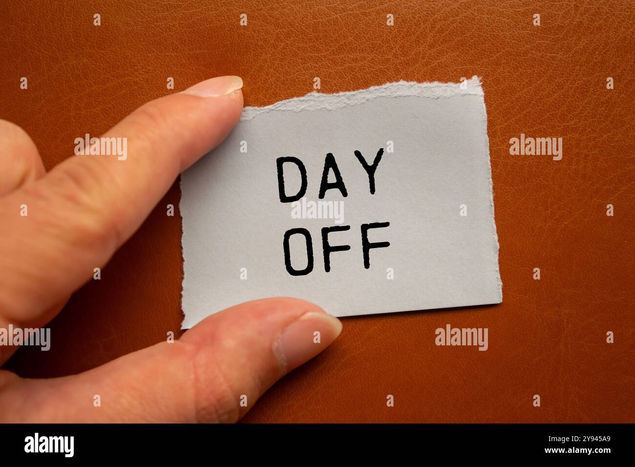 Day off message written on ripped torn paper piece on brown background ...