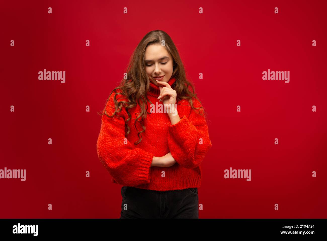 Thoughtful cute emotional young woman in a red sweater on a red ...