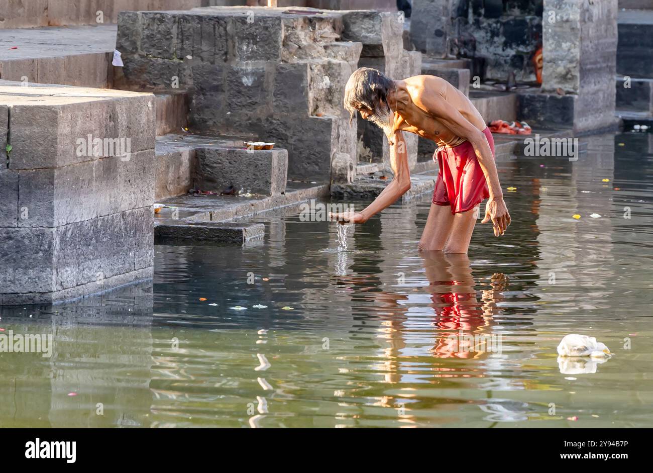hindu devotee old man bathing at pristine holy Shipra river at morning ...