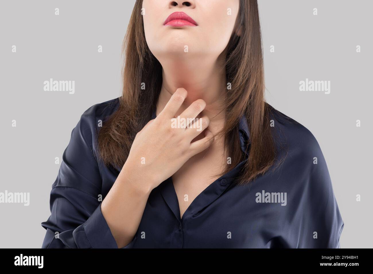 A woman is seen scratching her throat, suggesting an itch that might be ...