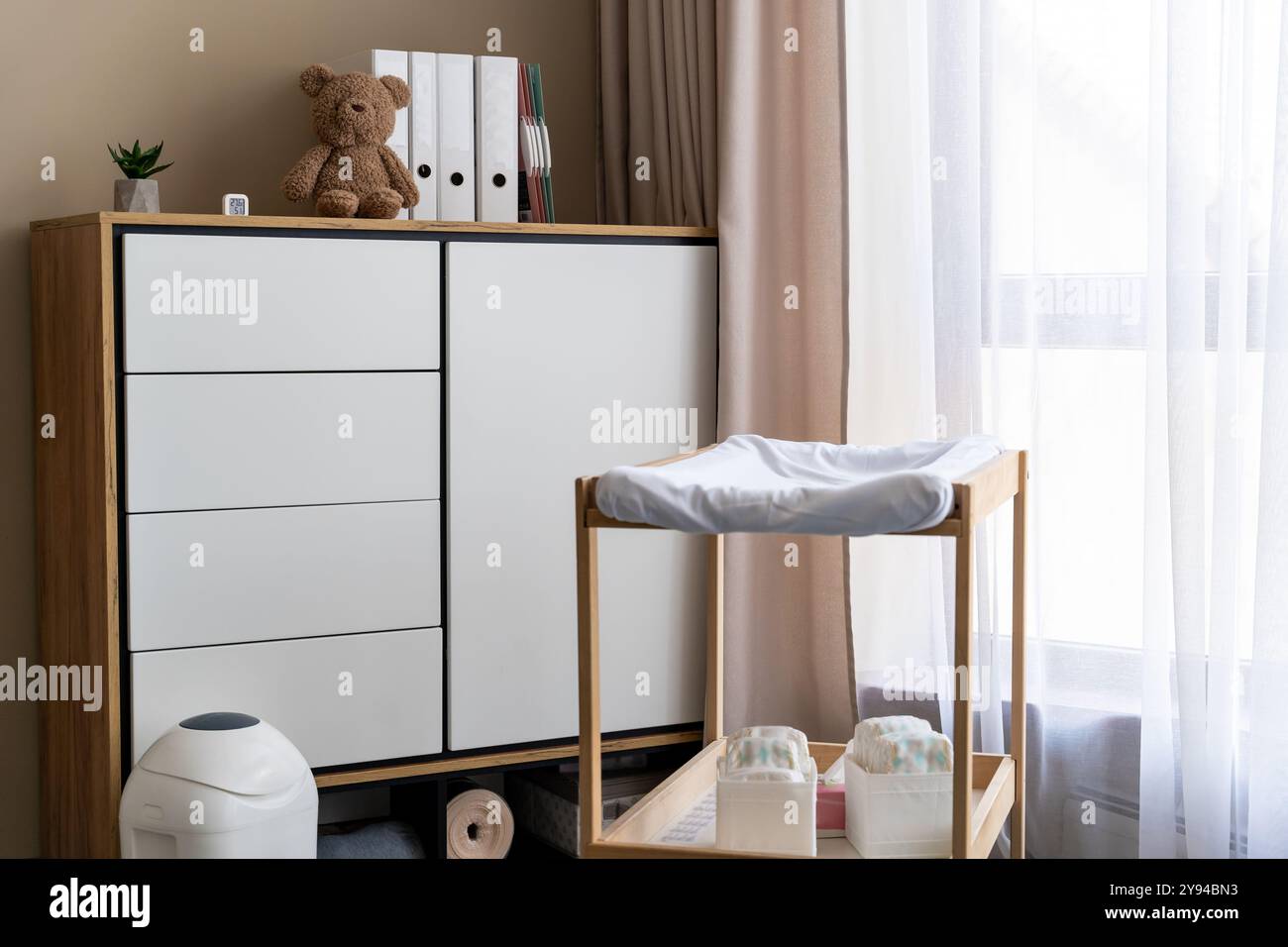 Empty nursery with changing table with diapers, lamp, commode and ...