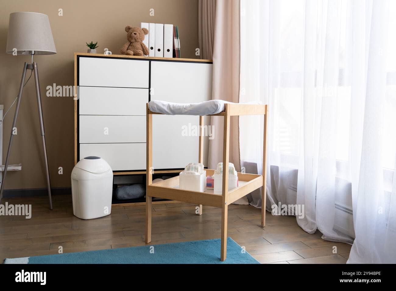 Empty nursery with changing table with diapers, lamp, commode and ...