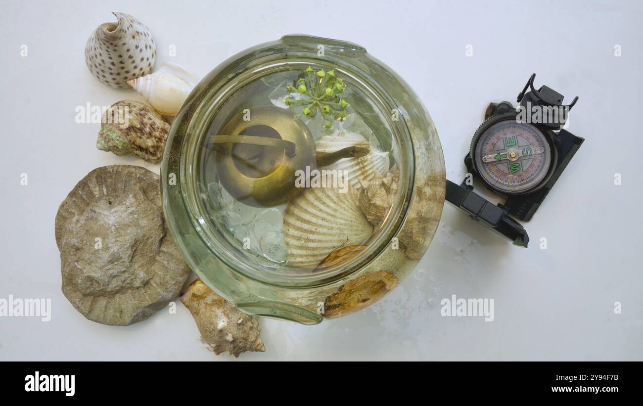A glass jar filled with water. A tiny teapot, seashells, a compass ...
