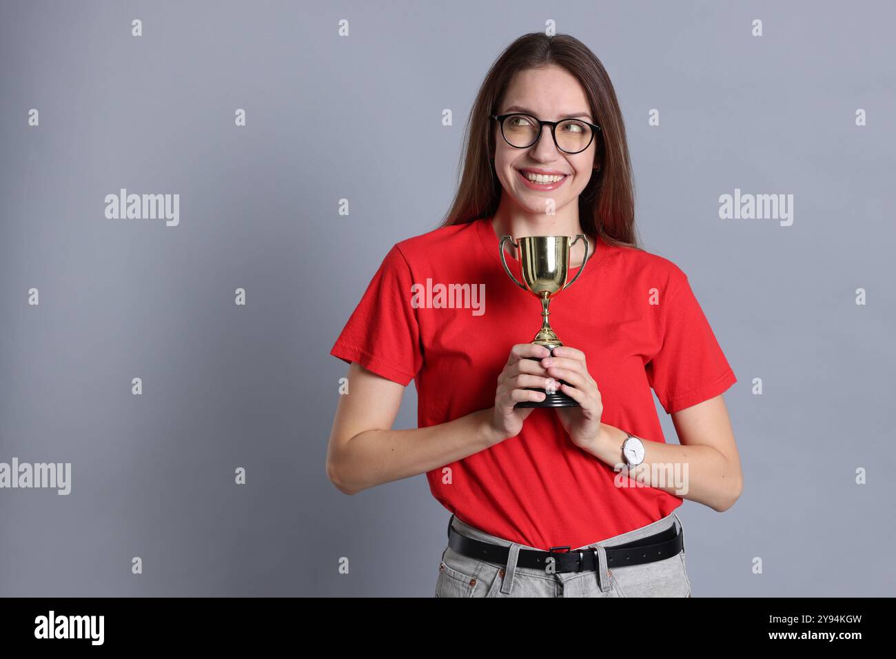 Happy winner with gold trophy cup on gray background Stock Photo - Alamy