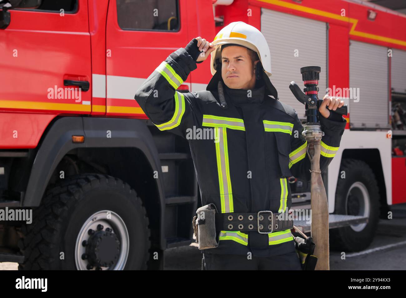 Firefighter in uniform with high pressure water jet near fire truck ...