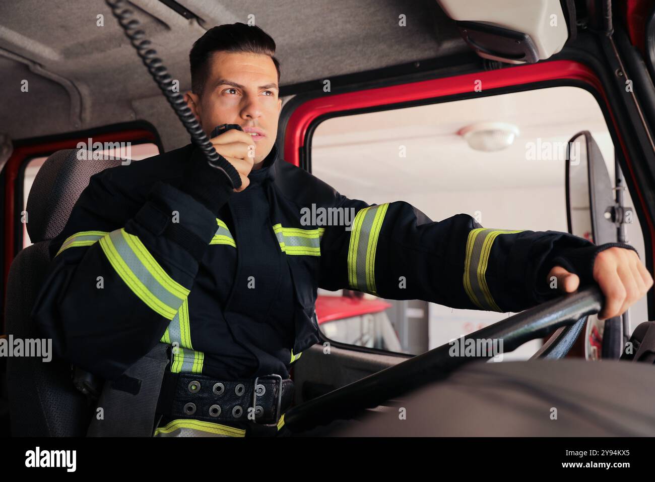 Firefighter using radio set while driving fire truck Stock Photo - Alamy