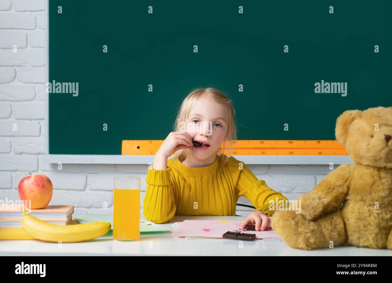 Little school girl student eating chocolate in class, study english ...