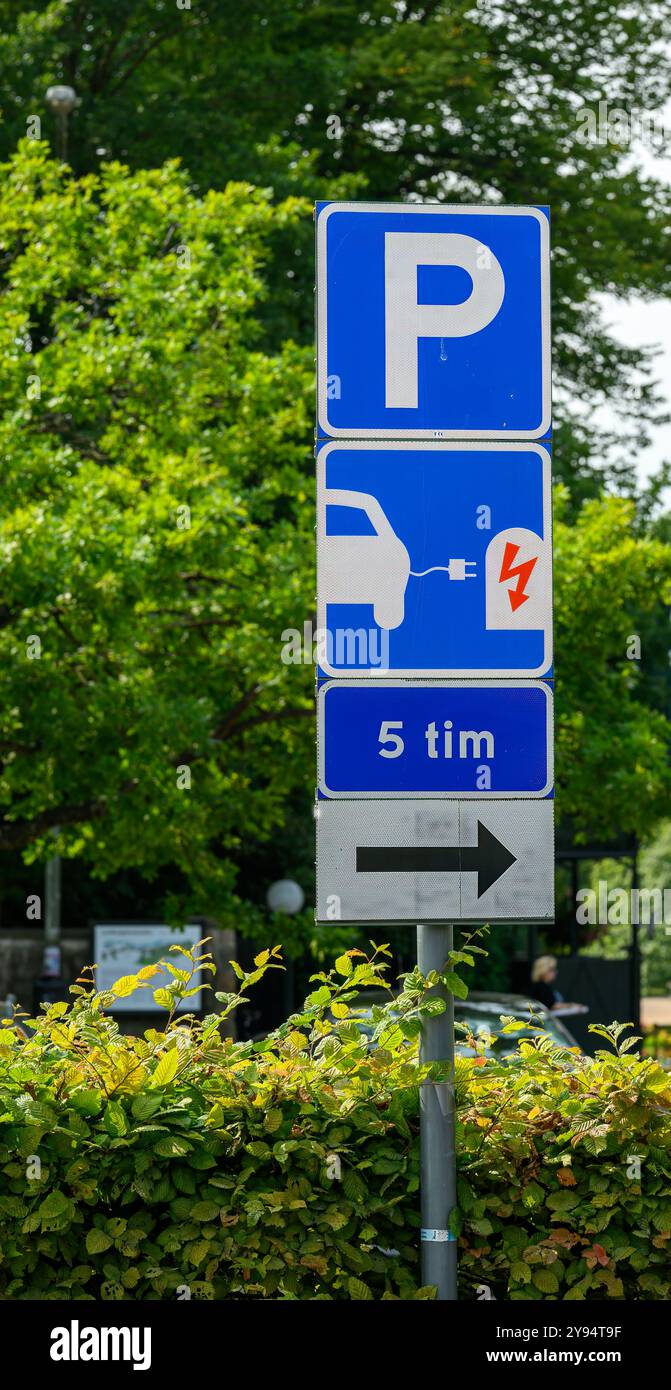 A parking sign displays electric vehicle charging symbols alongside a ...