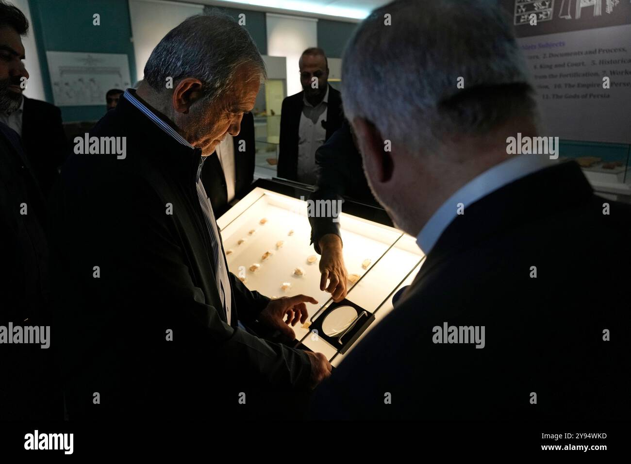 Iranian President Masoud Pezeshkian, left, looks at ancient clay ...
