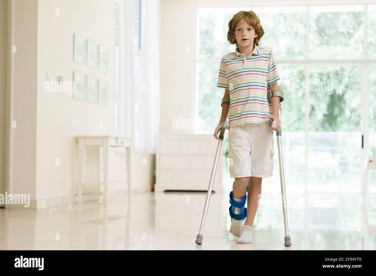 Injured child on crutches. Boy in cast on foot and leg. Little kid with ...